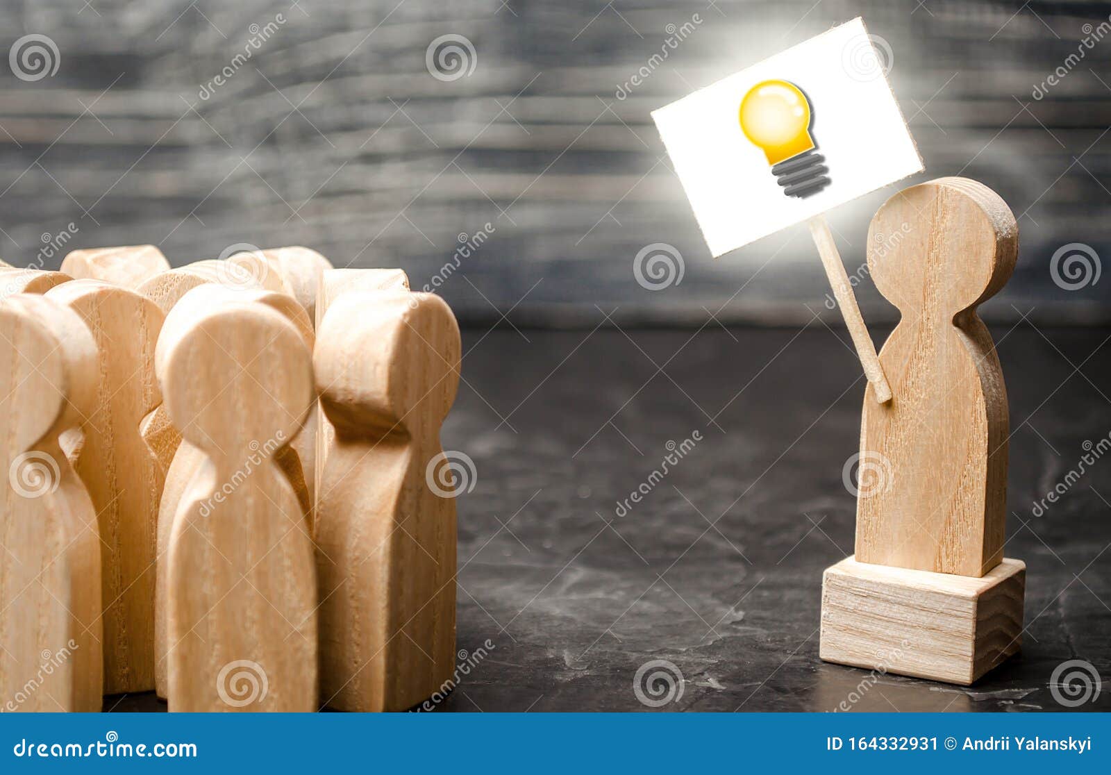 A Person with an Idea Light Bulb Sign Agitates a Group of People. the ...