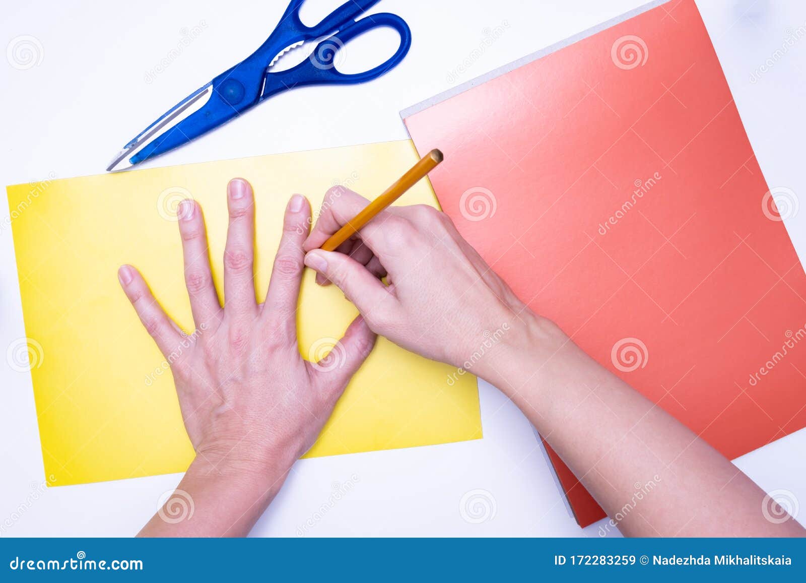 A Person Making Crafts of Colored Paper, Using Pencil and Scissors ...