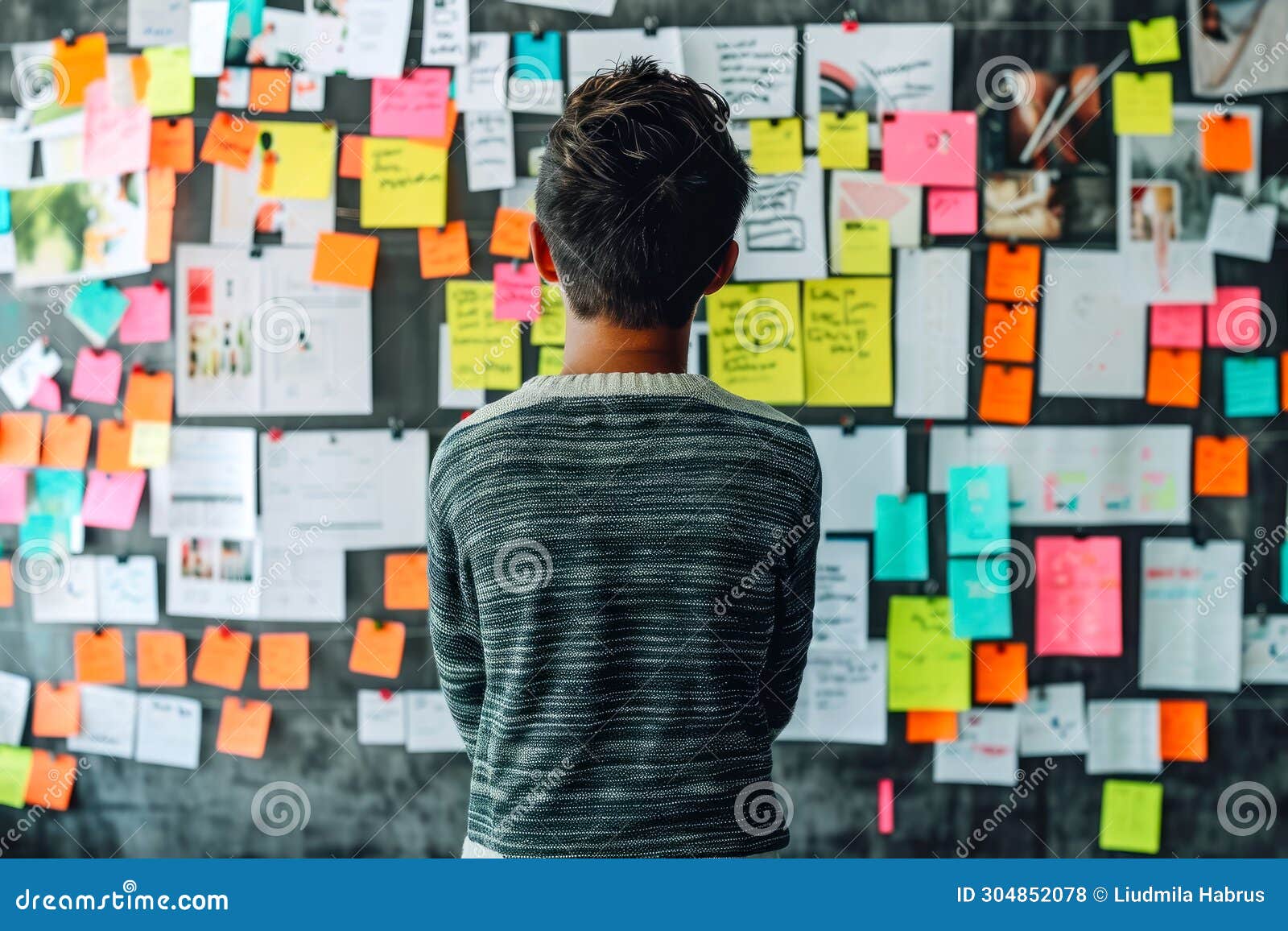 Person Standing in Front of a Wall Covered in Sticky Notes, Organizing ...