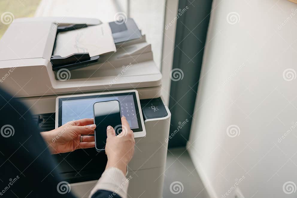 A Person Uses a Smartphone To Operate a Modern Printer in a Corporate ...