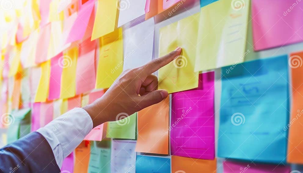 A Person is Using Hand Gestures To Point at a Pink Postit Note Attached ...
