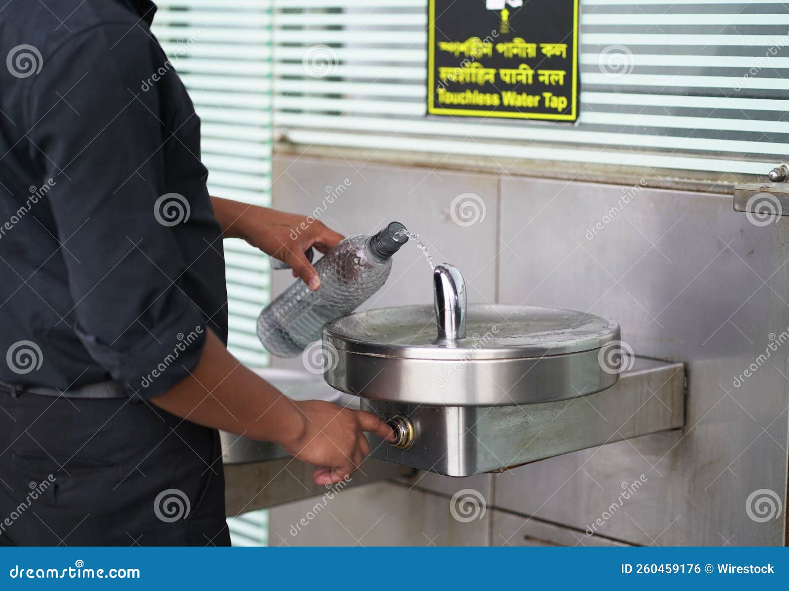 Persona Llenando Una Botella Desde Un Lavabo Dentro De Un Edificio Foto ...