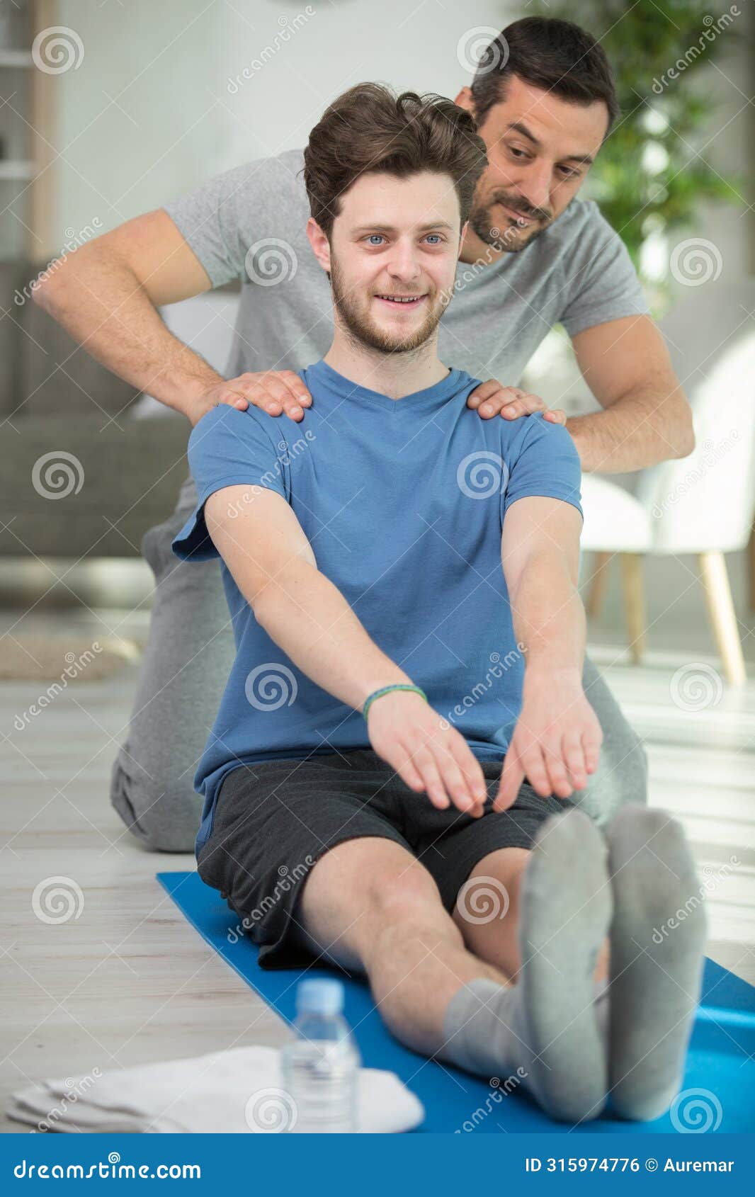 Personal Trainer Guiding Young Man during Floor Exercises Stock Photo ...
