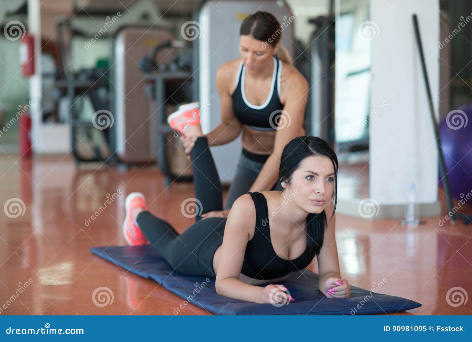Personal Trainer Helping Girl In Leg Stretching Workout At Gym Fitness