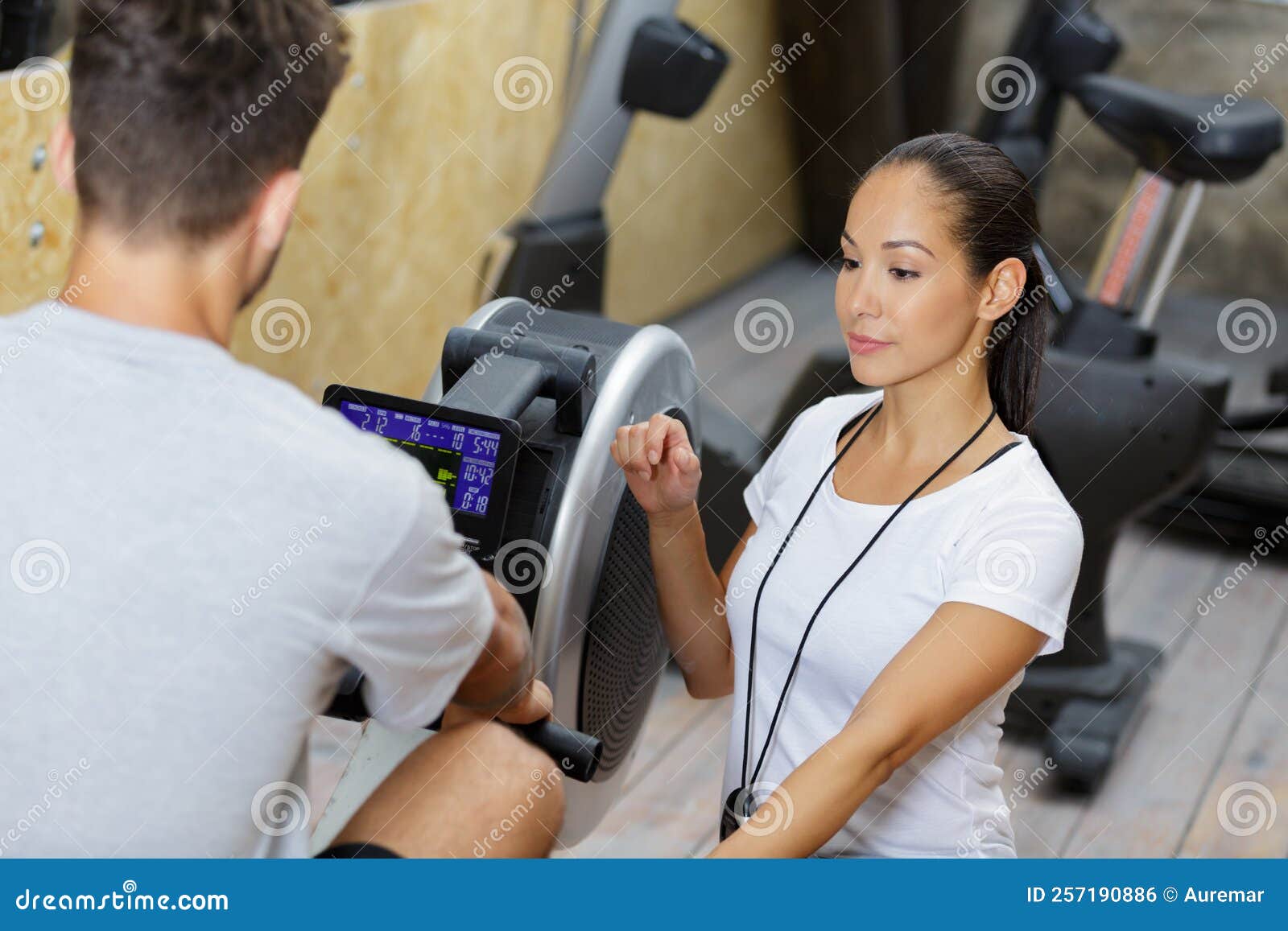 Personal Trainer Helping Male Client Using Rowing Machine Stock Photo ...