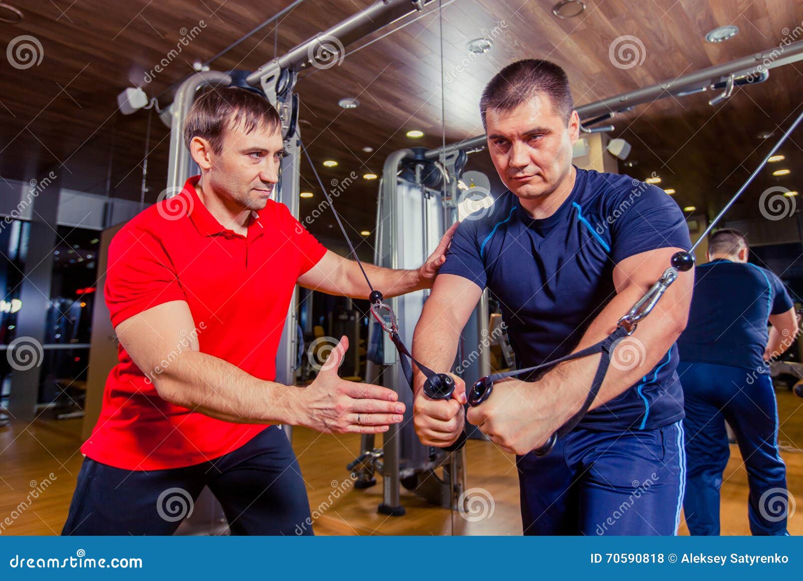 Personal Trainer Helping Men Working Out in Weights Room at the Gym ...