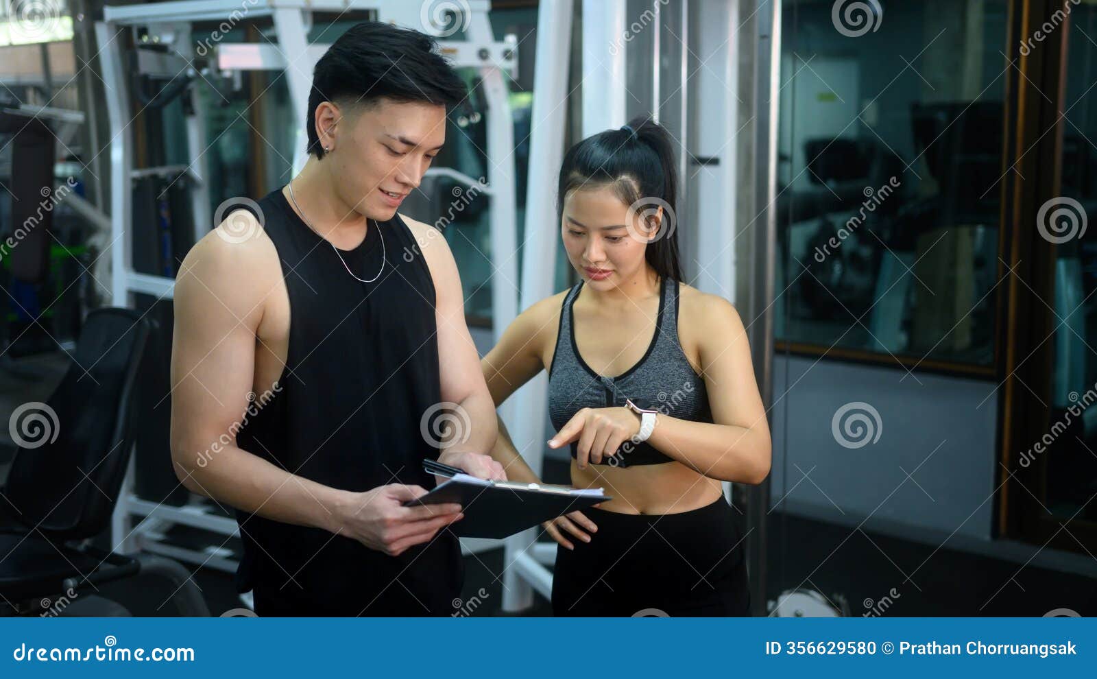 Personal Trainer and His Client Reviewing Workout Progress in the Gym ...