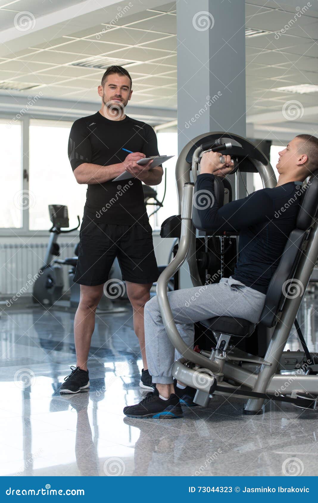 Personal Trainer Takes Notes while Man Exercising Chest Stock Image ...