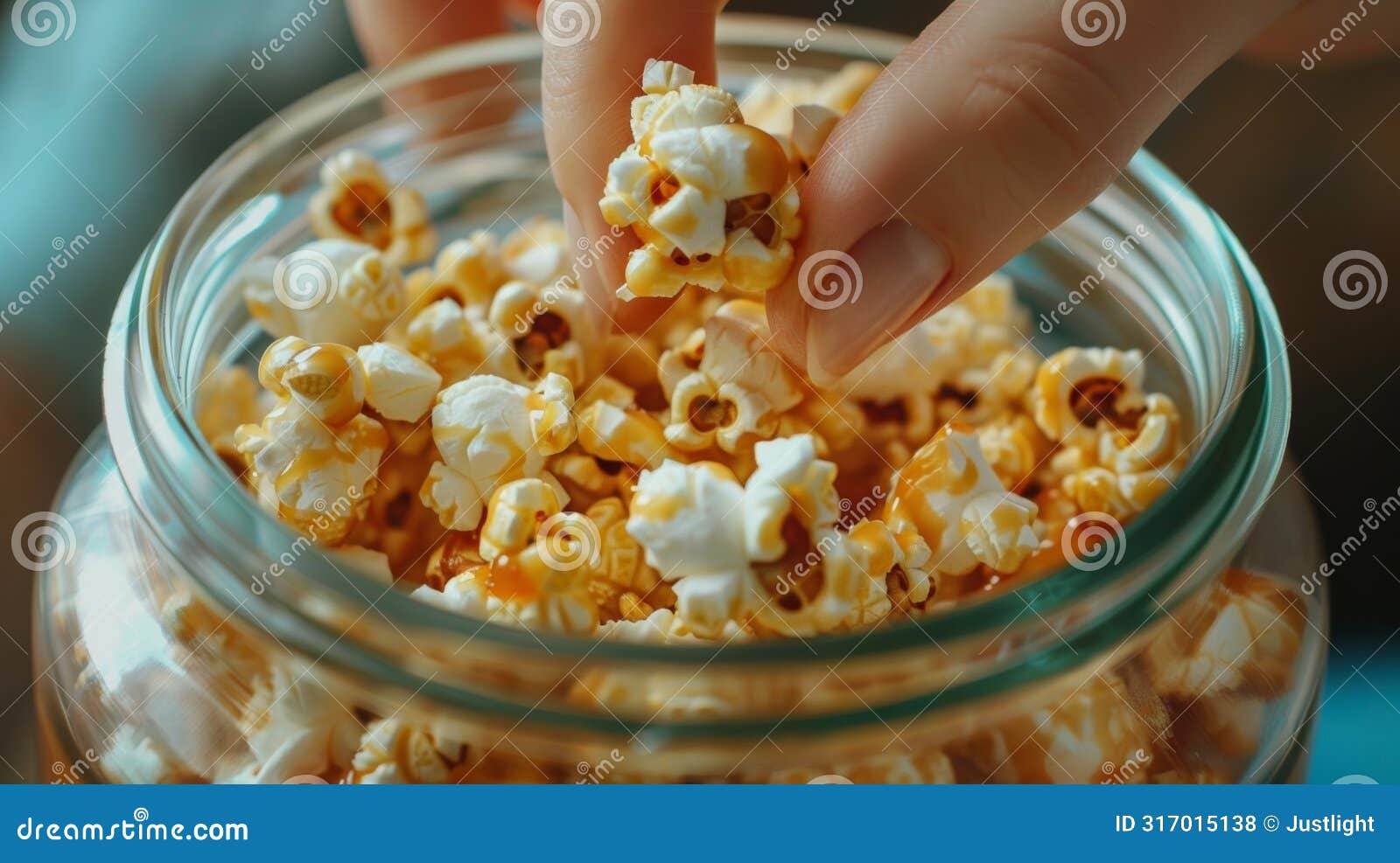 A Persons Hand Reaching into a Jar of Caramel Popcorn Ready To Take a ...