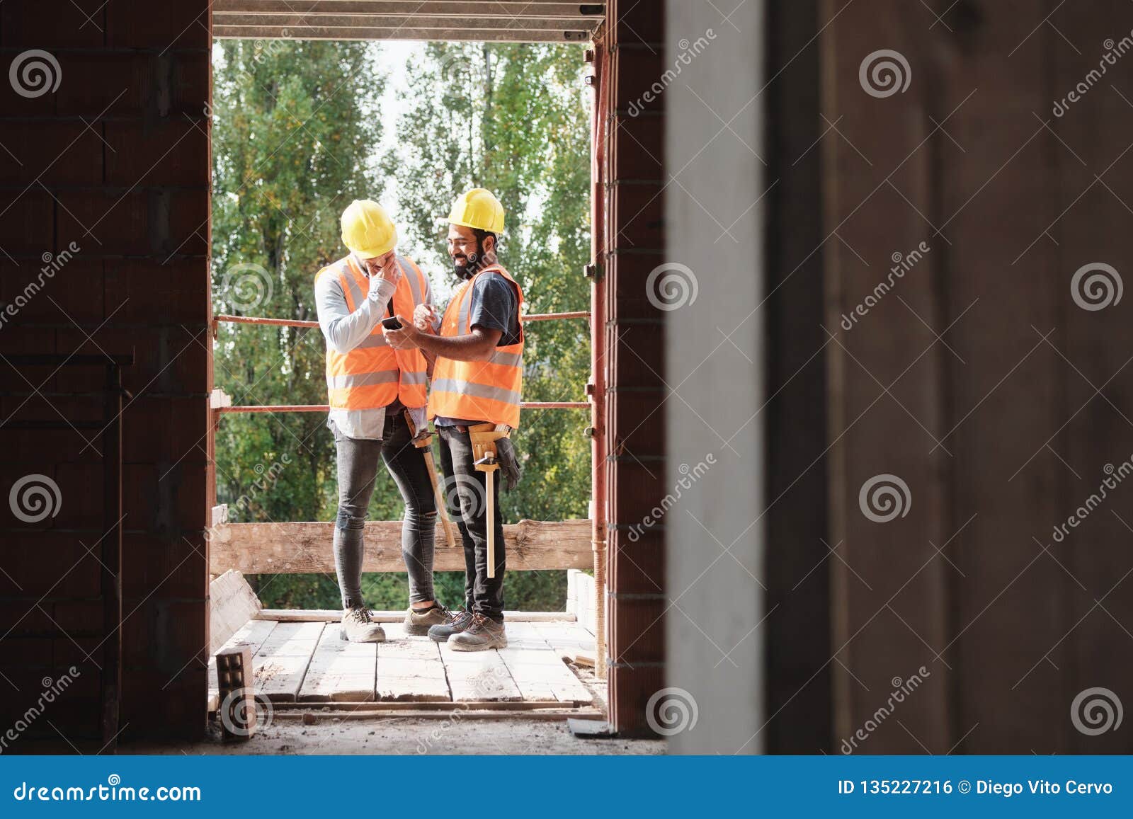 Happy Coworkers Laughing with Smartphone in Construction Site Stock ...