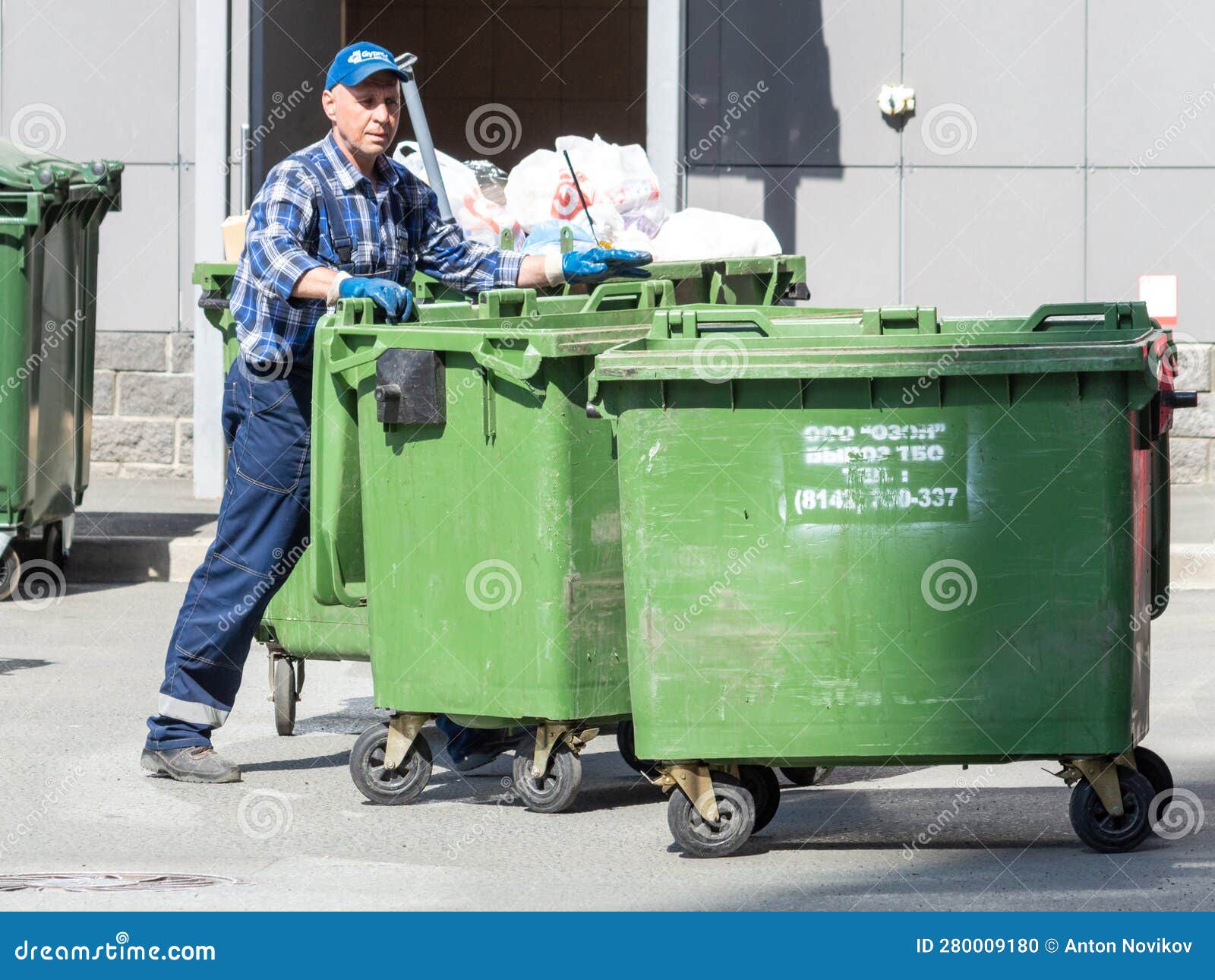 Two Refuse Collection Workers Loading Garbage Into Waste Truck Emptying ...