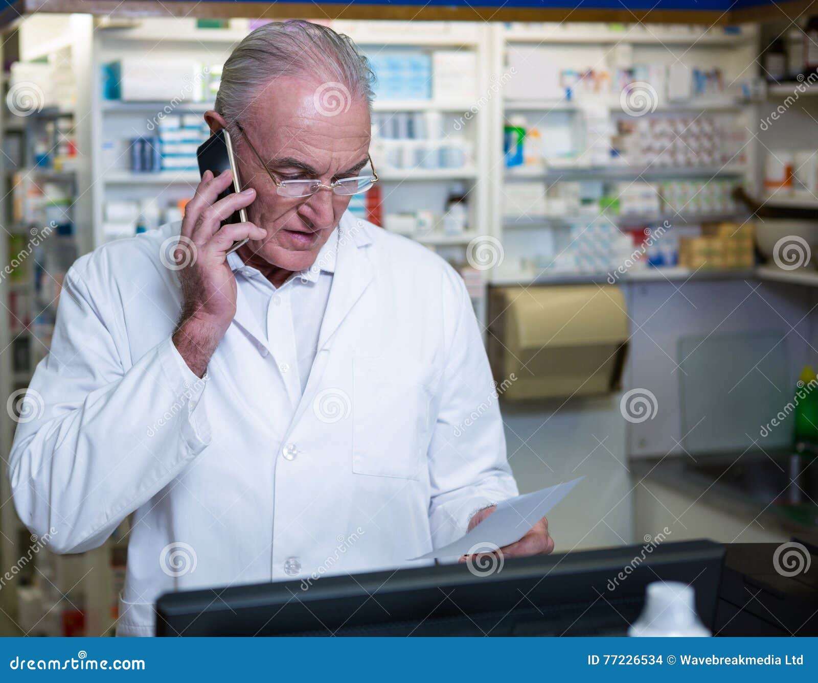 Pharmacist Talking on Mobile Phone while Checking Prescription Stock ...