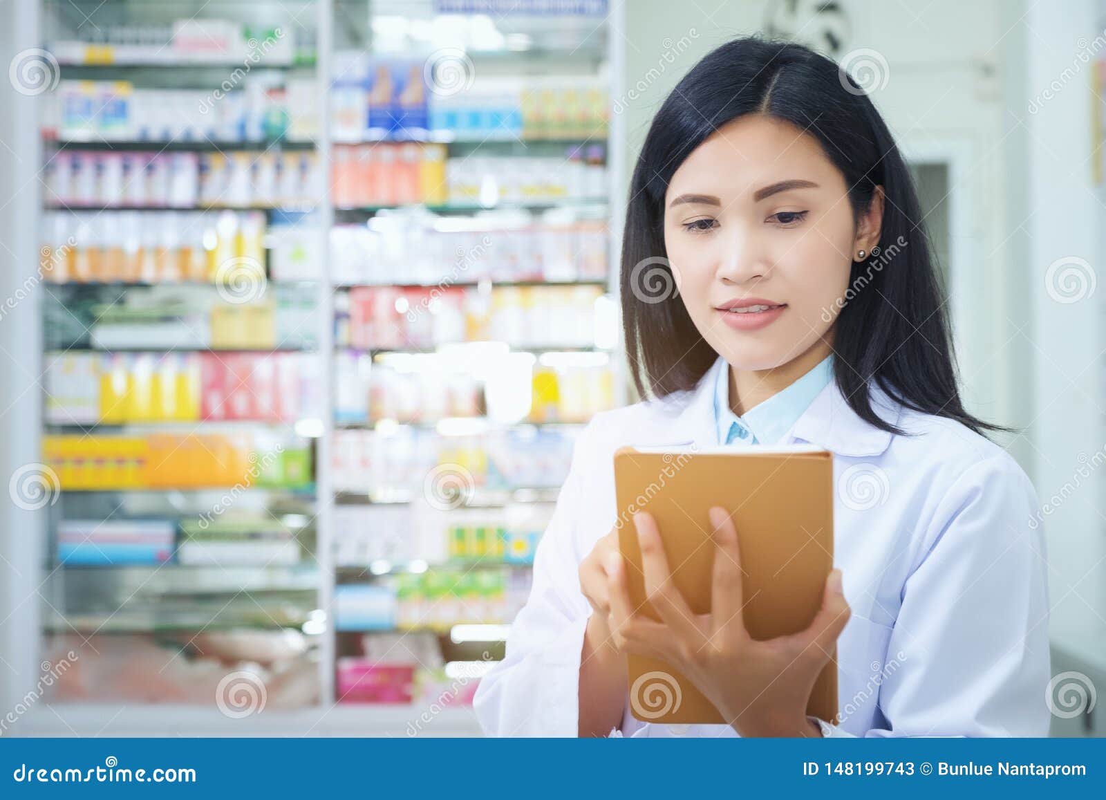 Pharmacist Working with a Tablet Computer in the Pharmacy Holding it in ...