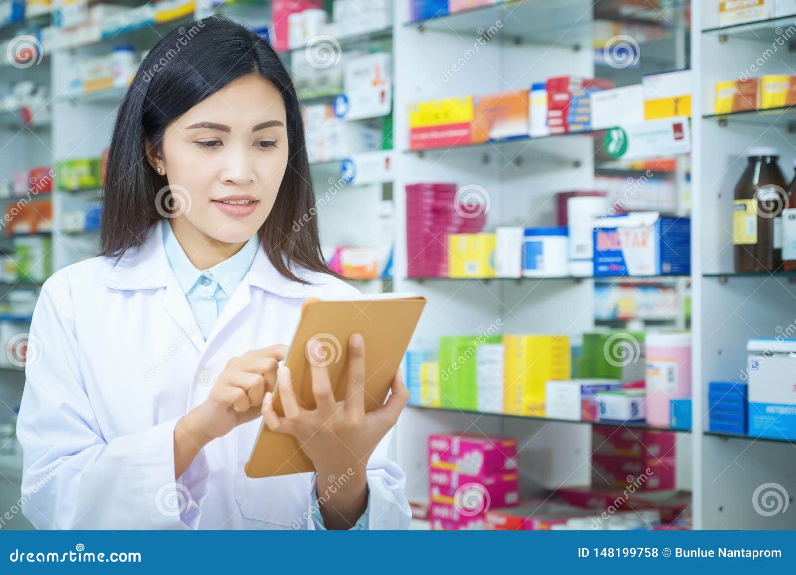 Pharmacist Working with a Tablet Computer in the Pharmacy Holding it in ...