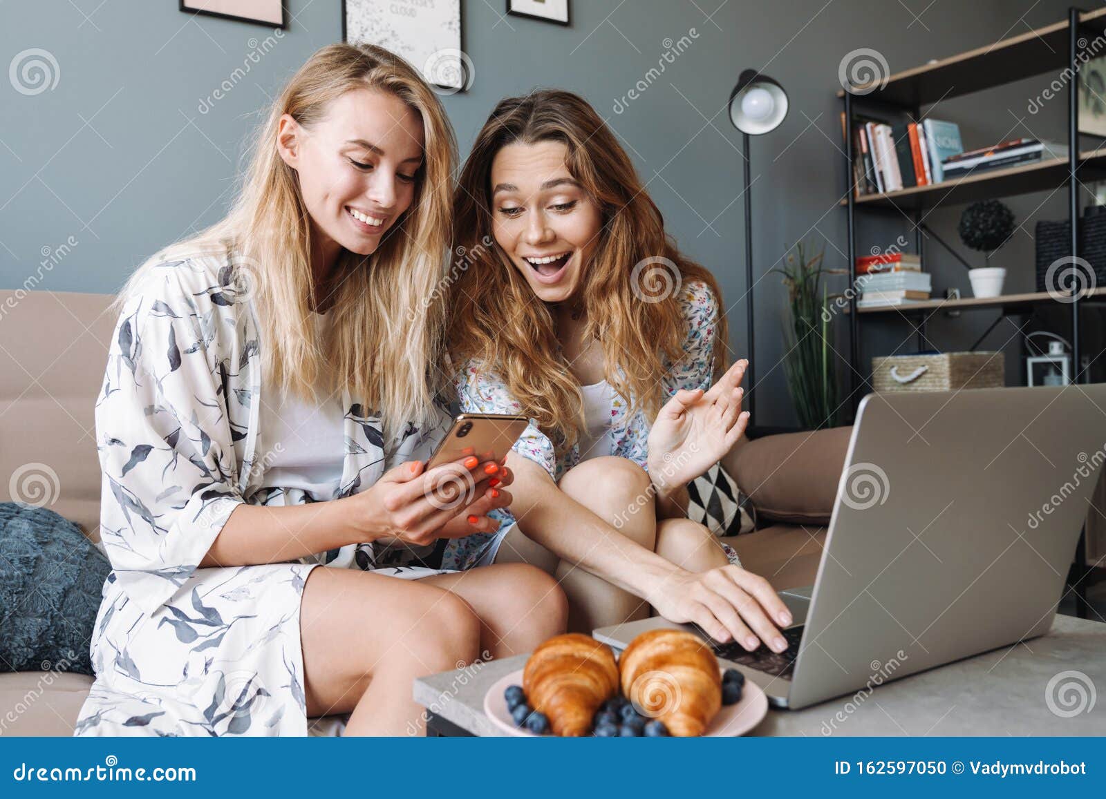 Cheerful Positive Women at Home Using Laptop Computer and Mobile Phone ... Cheerful Positive Women at Home Using Laptop Computer and Mobile Phone ...