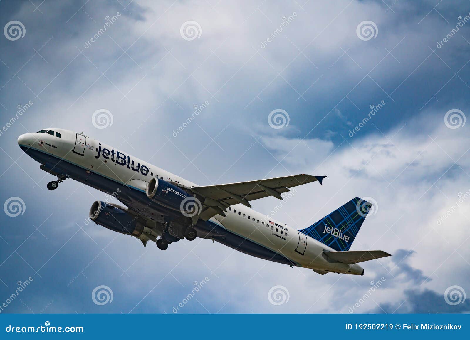 Photo Of A Jetblue Airplane On Sky Background Blue And Clouds ...