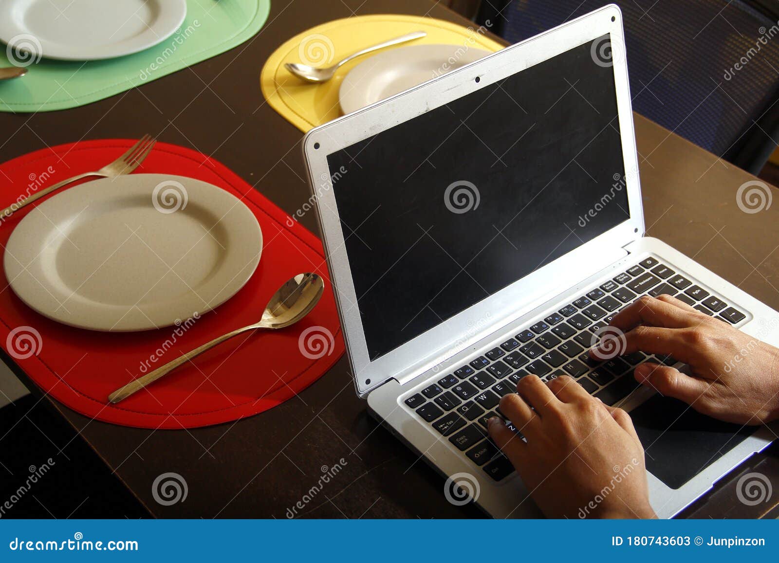 Laptop Computer with Hands Typing on it, Plates and Utensils on a ...