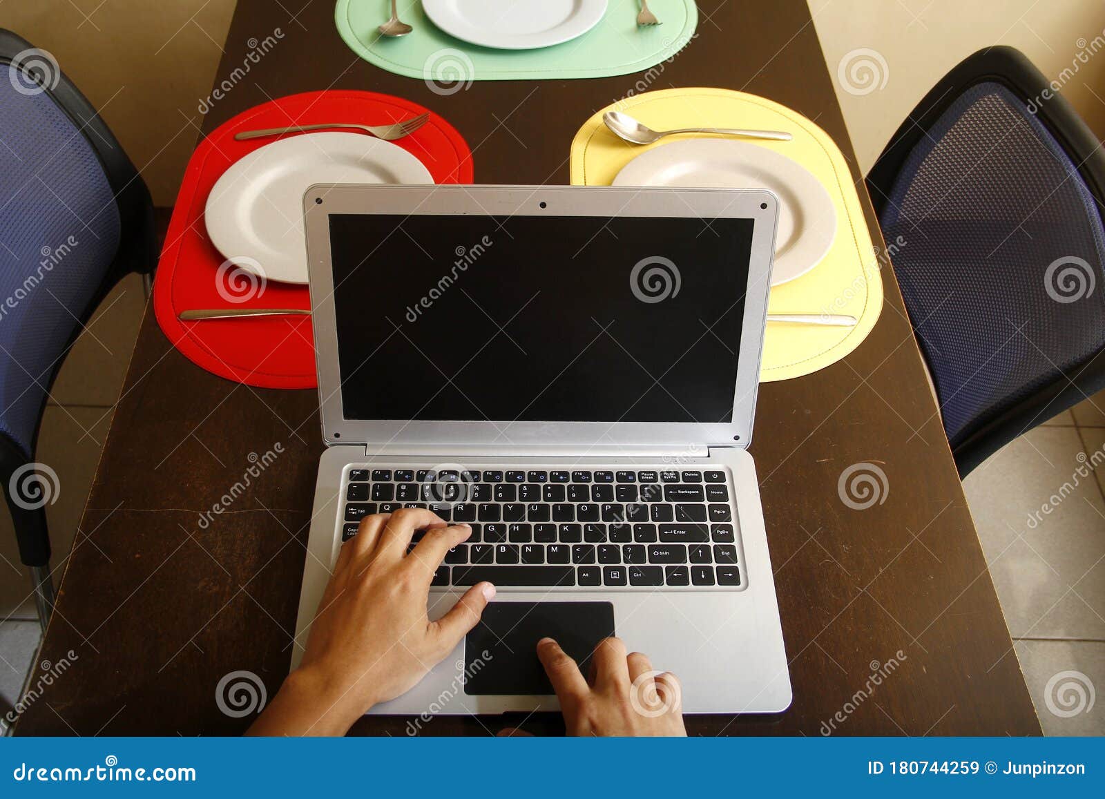 Laptop Computer with Hands Typing on it, Plates and Utensils on a ...