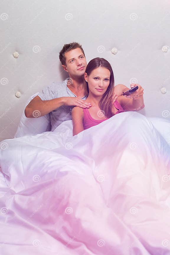 Man Massaging His Wife Shoulder While Watching Tv In Bed Stock Image