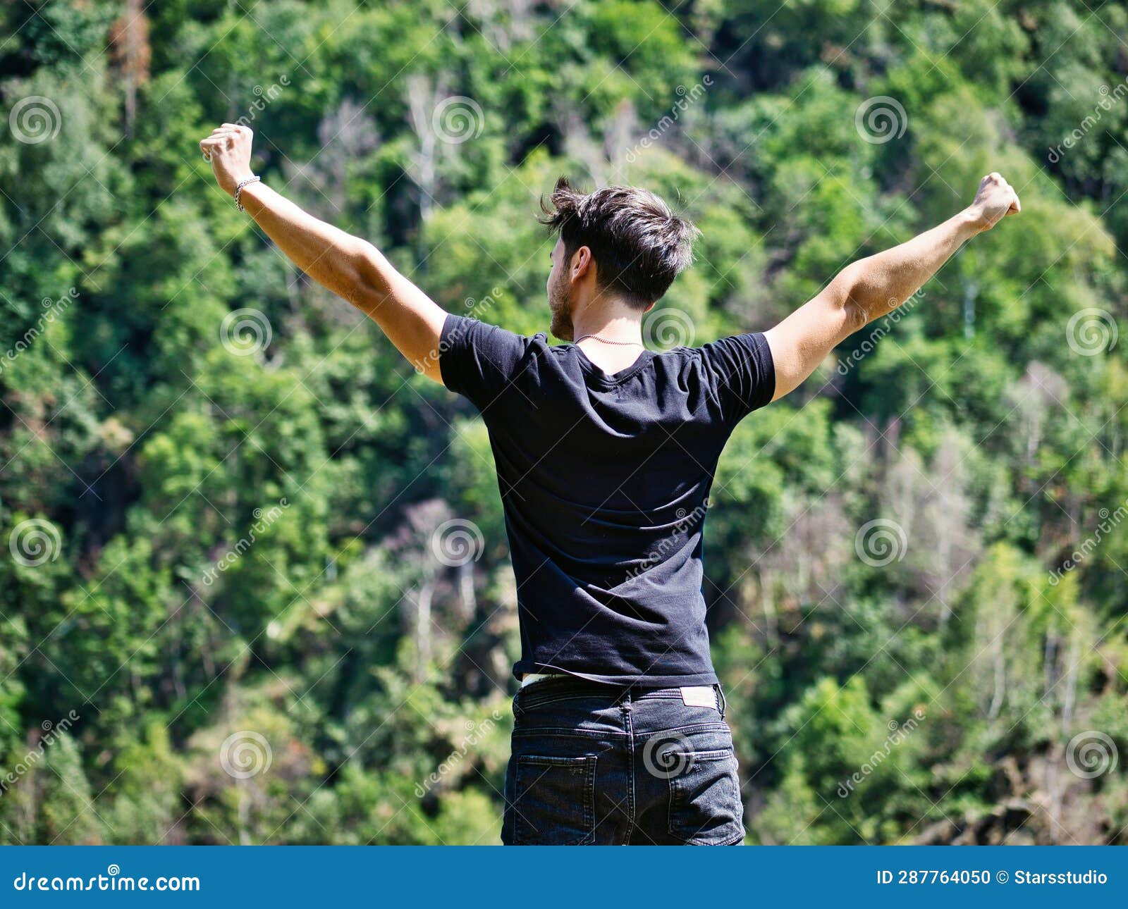 Photo of a Man Standing in Front of a Lush Green Forest Stock Photo ...