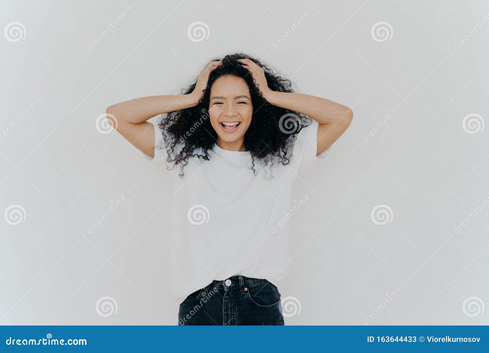 Photo Of Overjoyed Curly Haired Woman Laughs Happily Has Fun Dressed