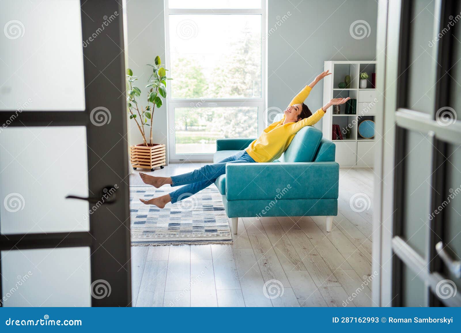 Photo Of Positive Cheerful Lady Sitting Divan Stretching Hands Enjoy