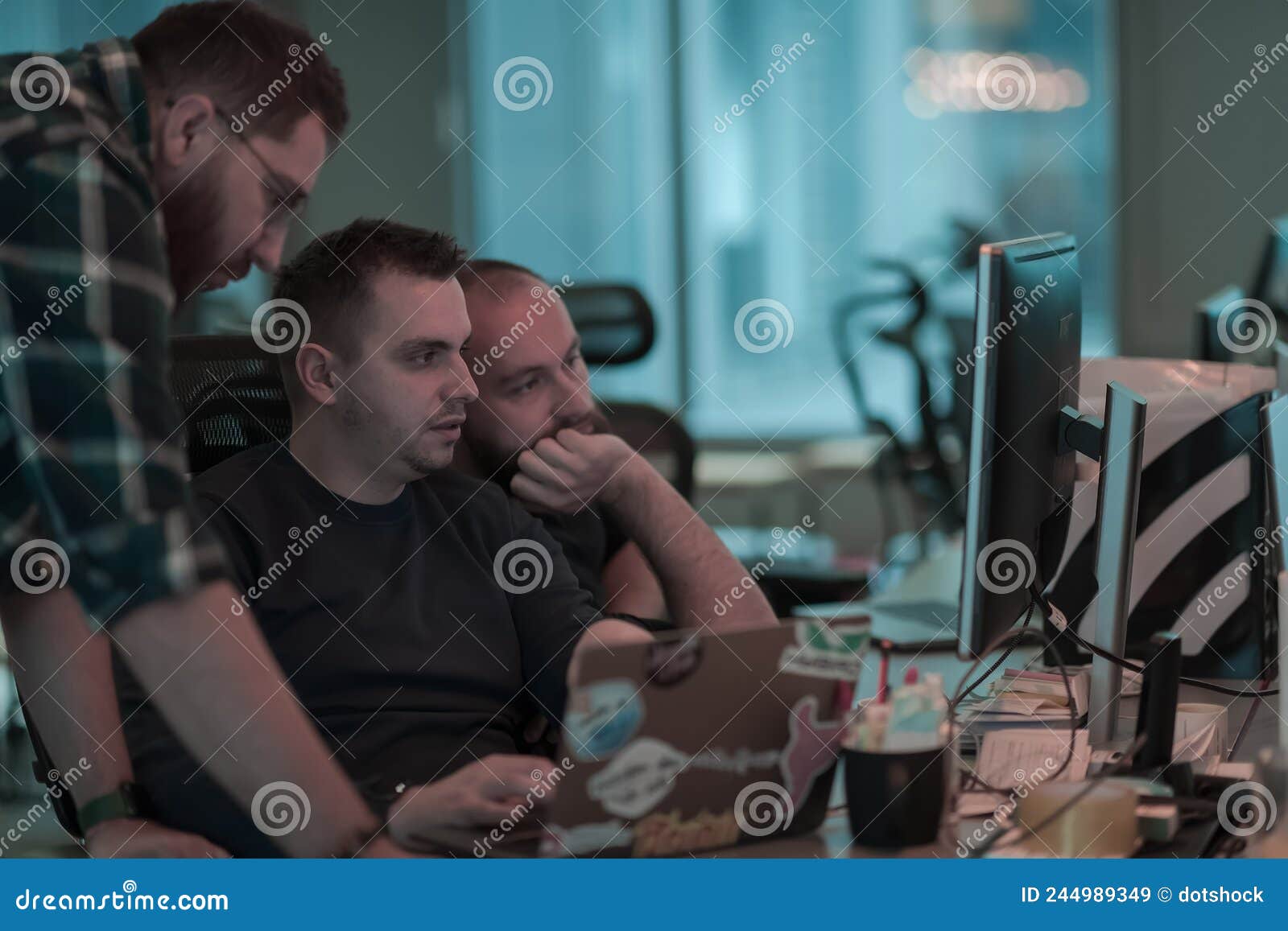 A Photo of Three Men Staring Intently at a Computer while Sitting in a ...