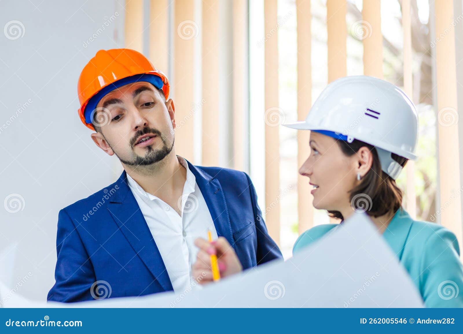 Photo of Two Engineers Wearing Helmets and Holding Paper with Plan ...