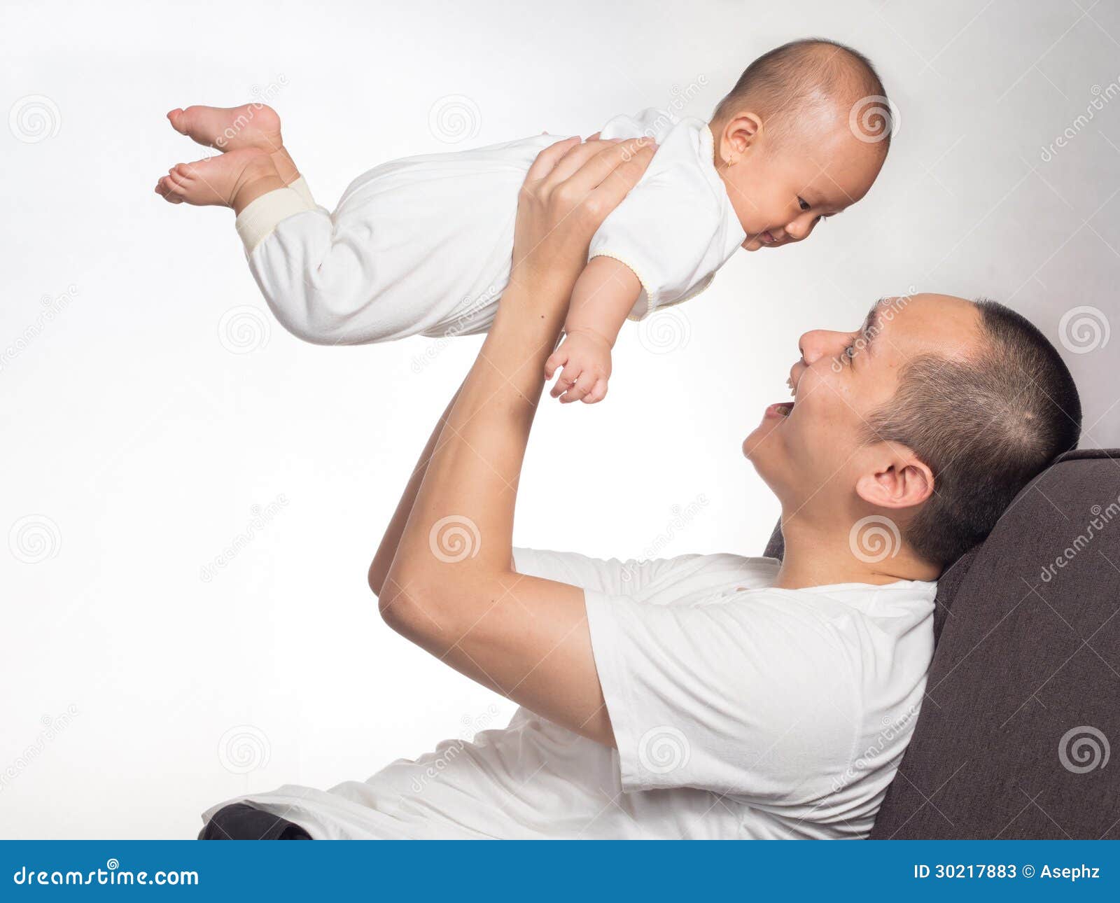 Father Lifting Baby on the Sofa Stock Image - Image of family, adorable ...