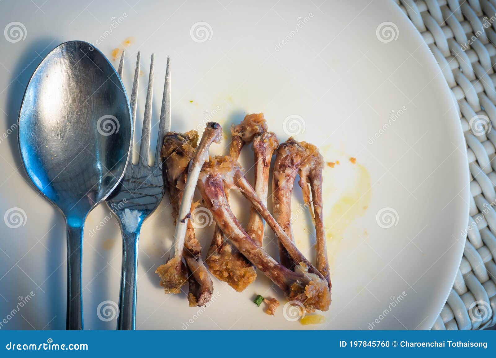 Picture of Fried Chicken Bones Placed with Spoon and Fork on a White ...