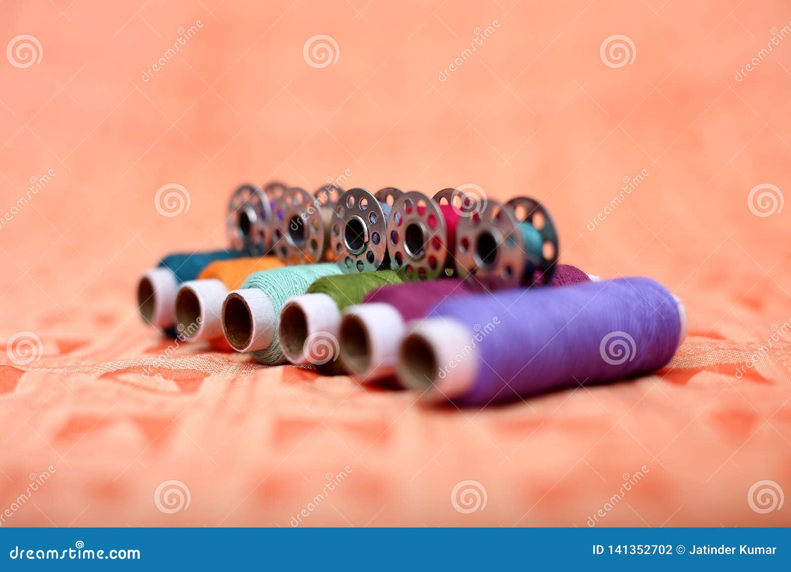 Picture of Multicolored Sewing Thread with Bobbin on the Orange Cloth ...