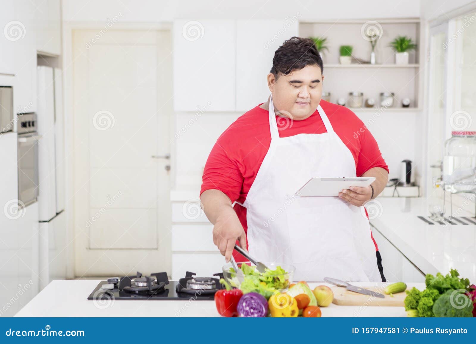Obese Man Using a Tablet and Preparing Salad Stock Image - Image of ...