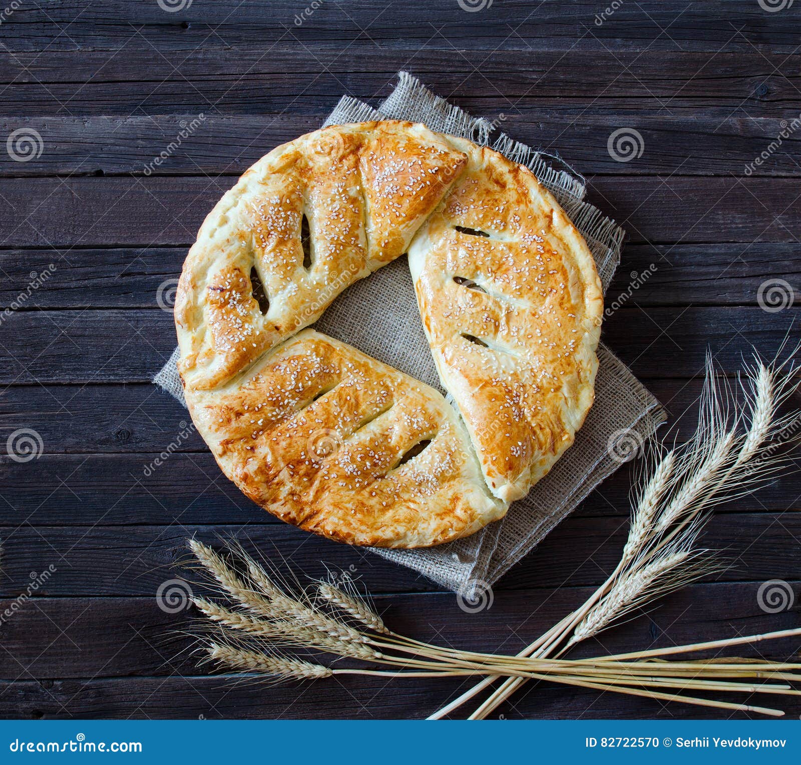 Pie with Sesame on a Sacking and Ears of Wheat. Dark Wooden Background ...