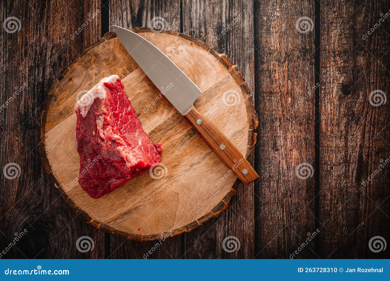 A Piece of Red Beef on a Rustic Wooden Table with a Sharp Knife. Top ...