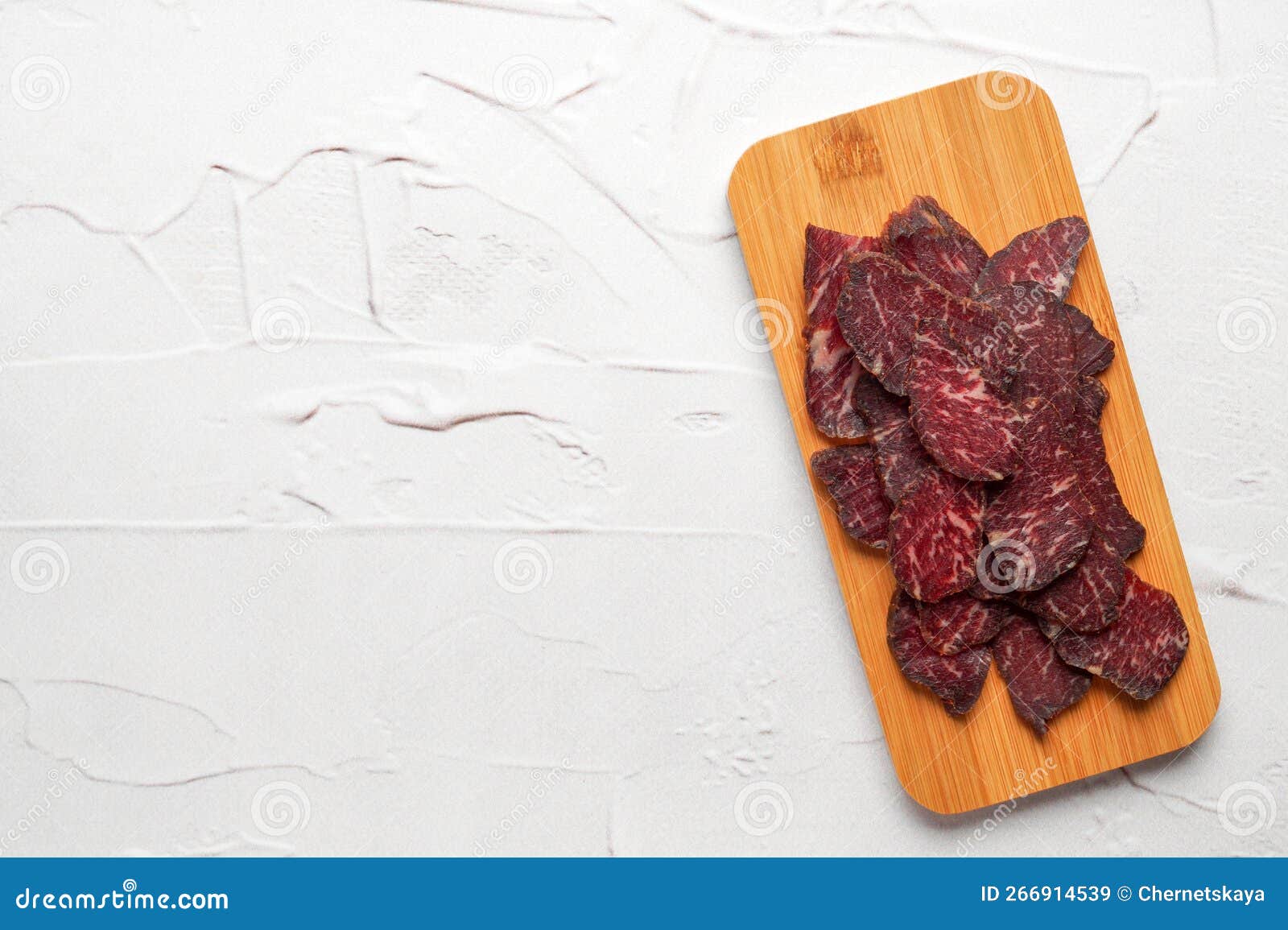 Pieces of Delicious Beef Jerky on White Textured Table, Top View. Space ...