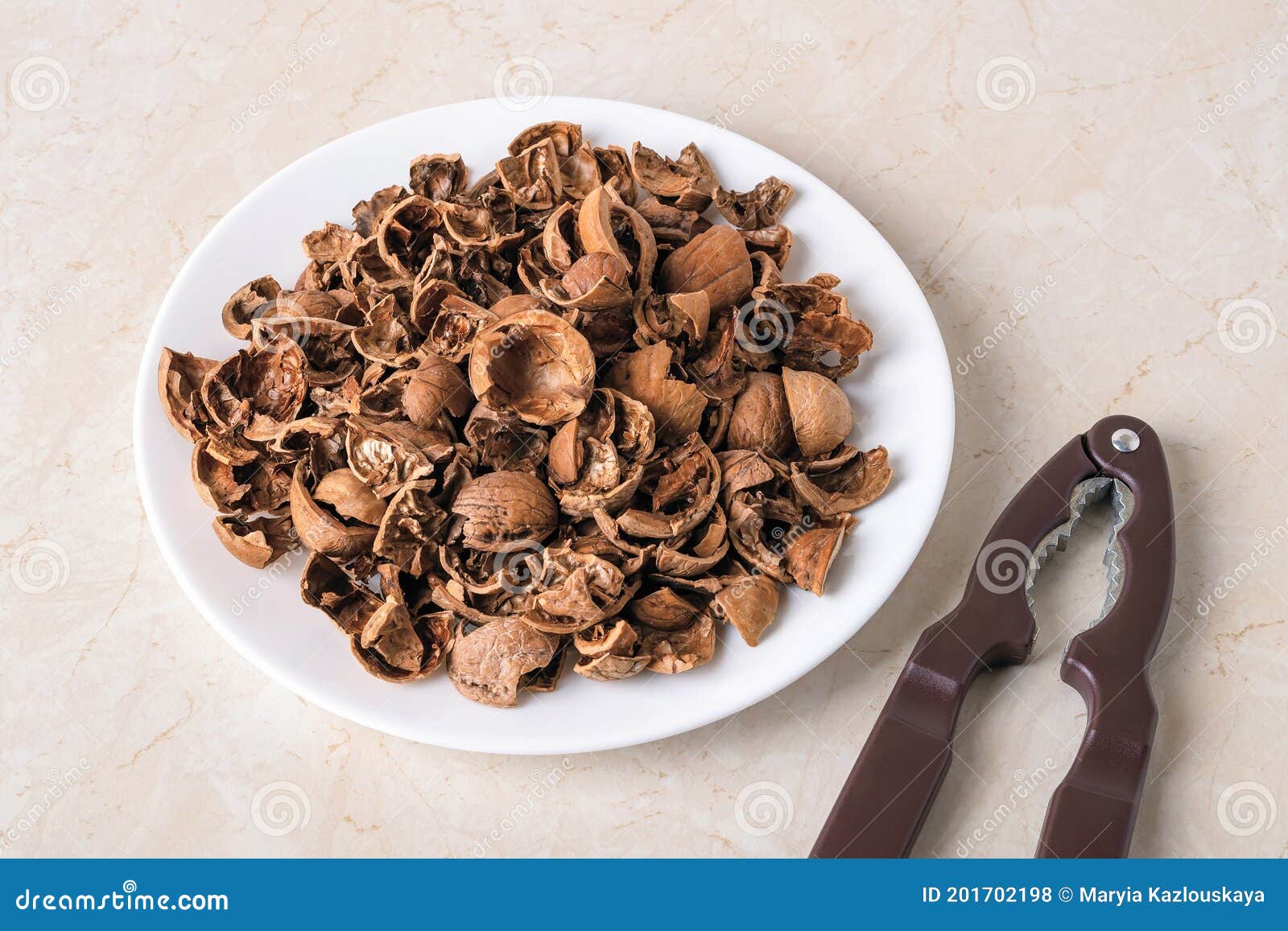 Pile of Empty Broken Walnut Shells on a White Plate and Nutcracker Over ...