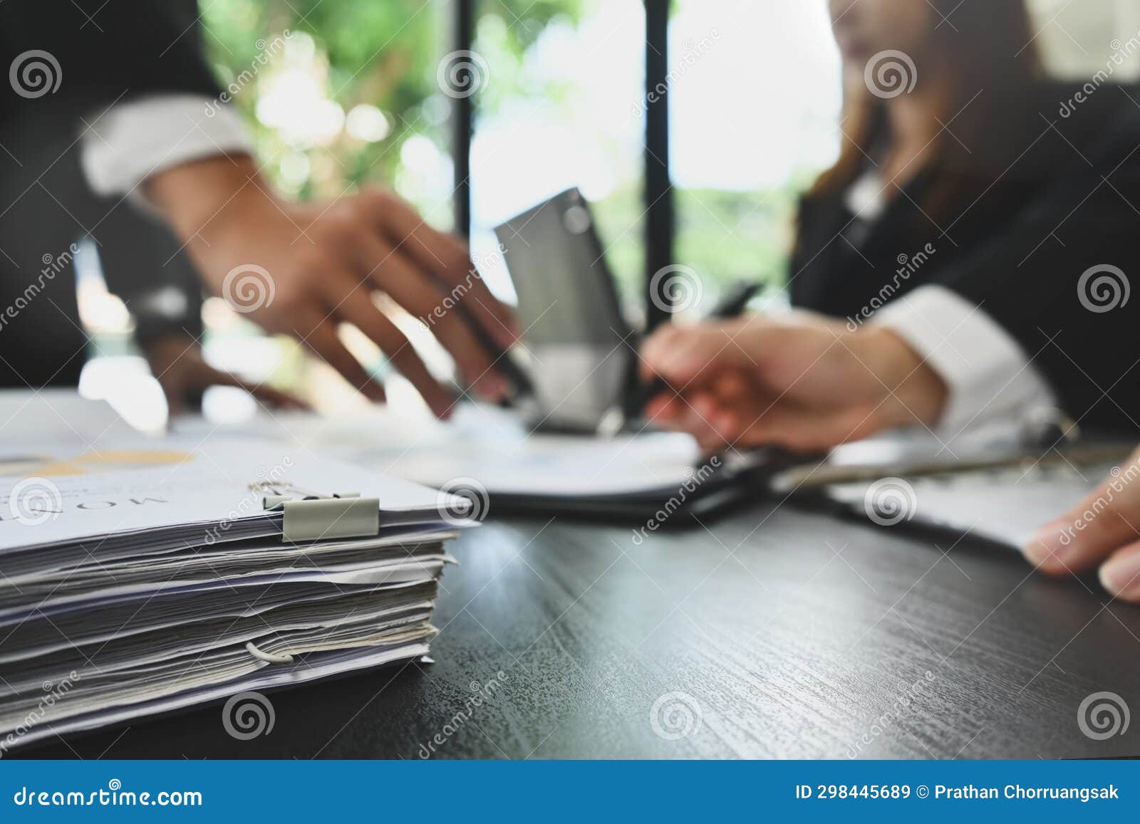 Pile of Paperwork on Meeting Table with Blurred Businesspeople Working ...