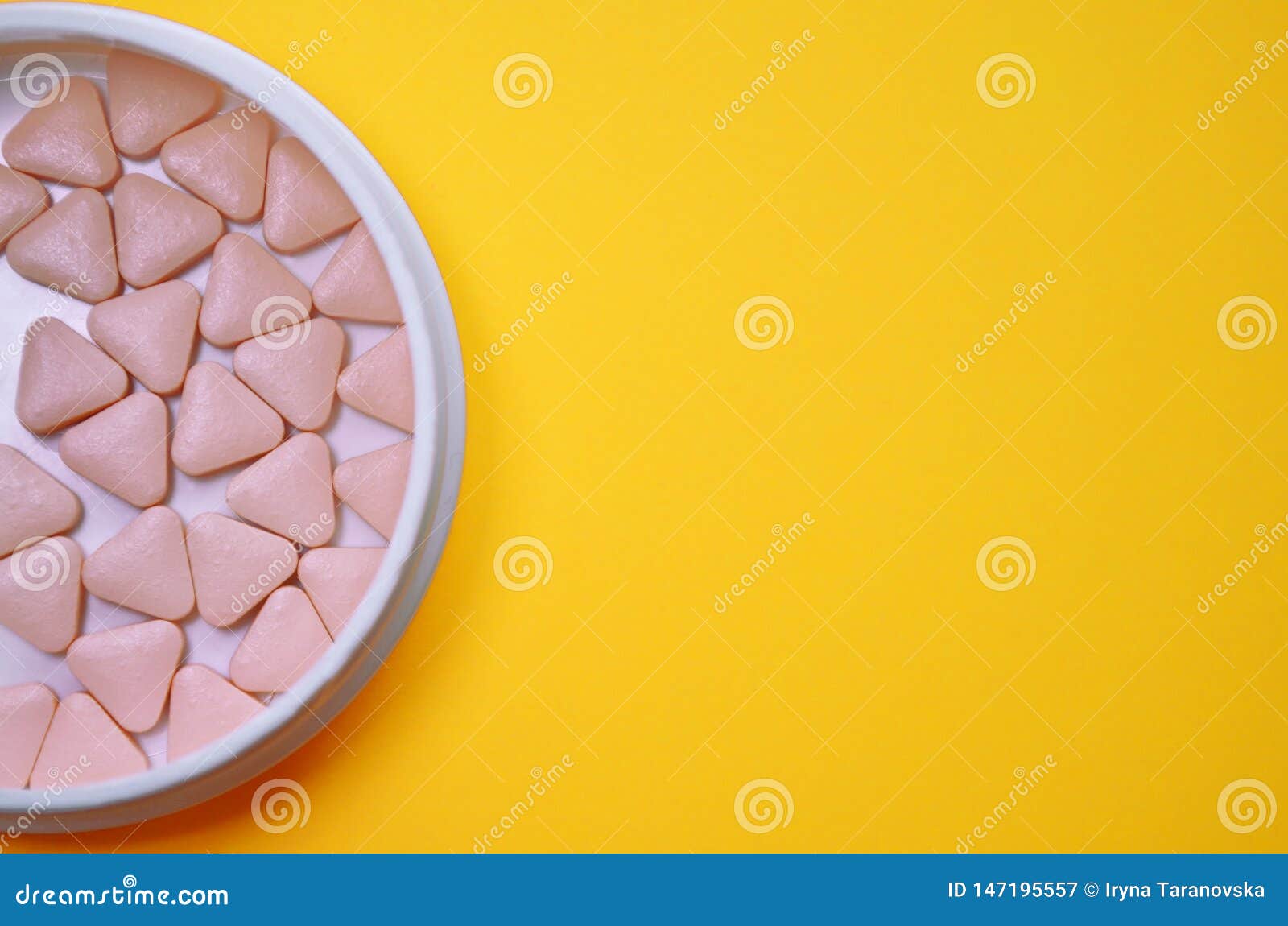 Pink Triangular Unusual Pills in a White Round Box on a Yellow ...