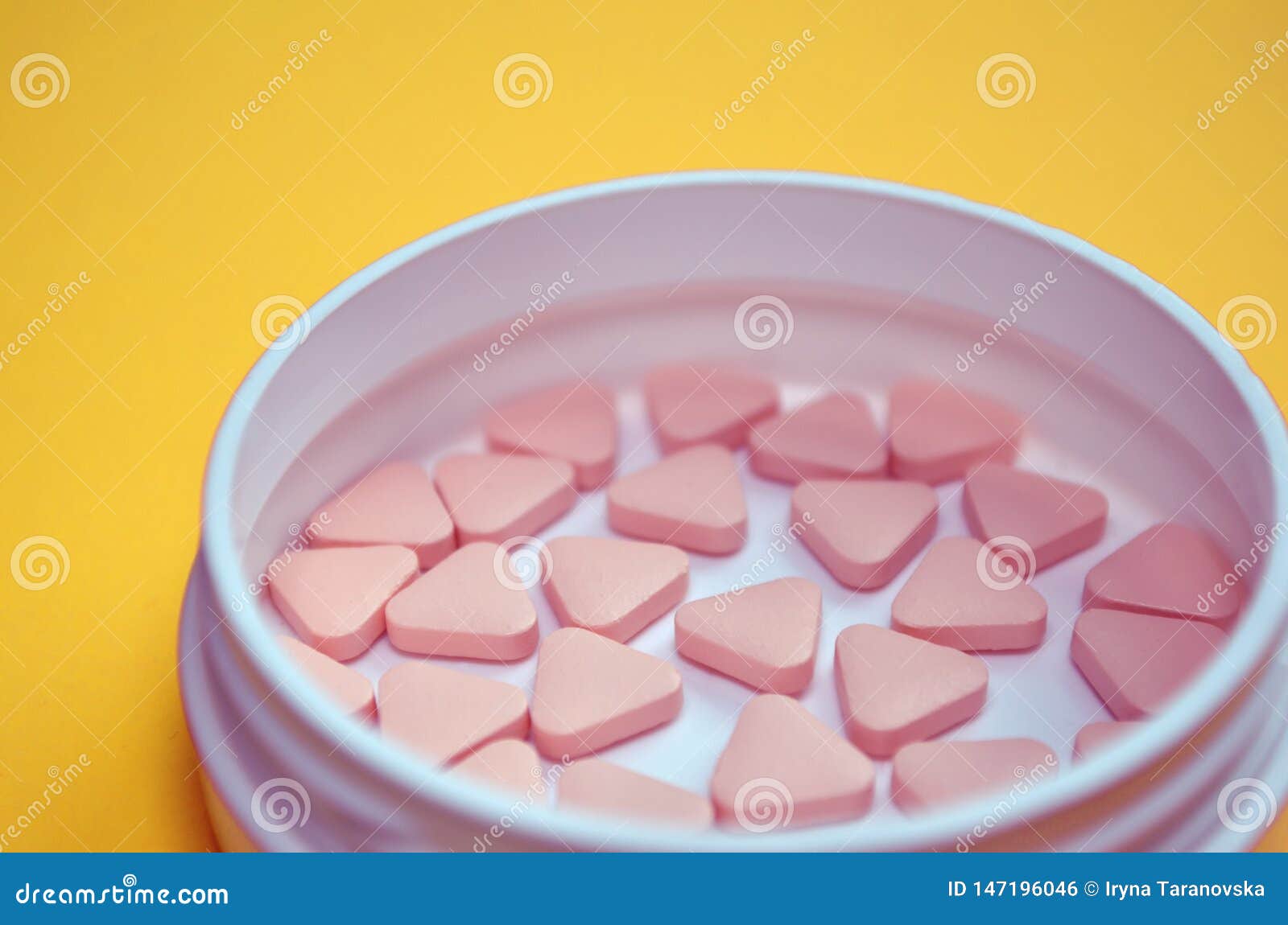 Pink Triangular Unusual Pills in a White Round Box on Yellow Background ...