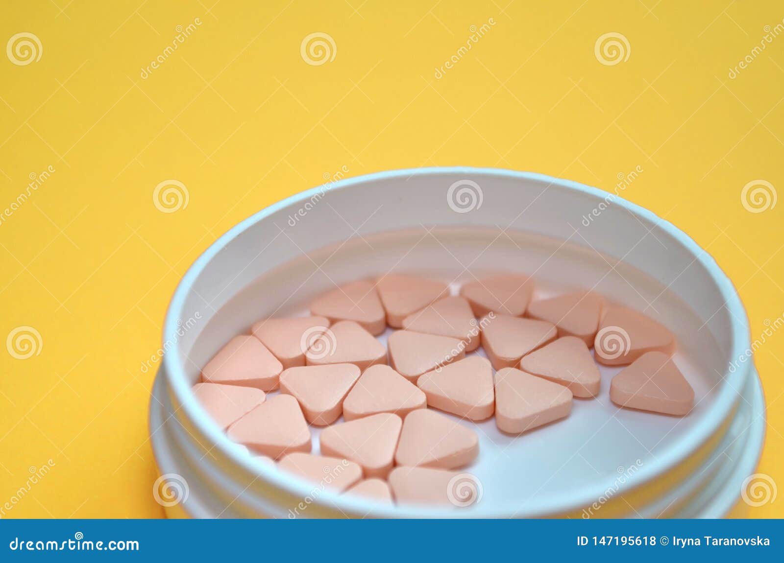 Pink Triangular Unusual Pills in a White Round Box on Yellow Background ...