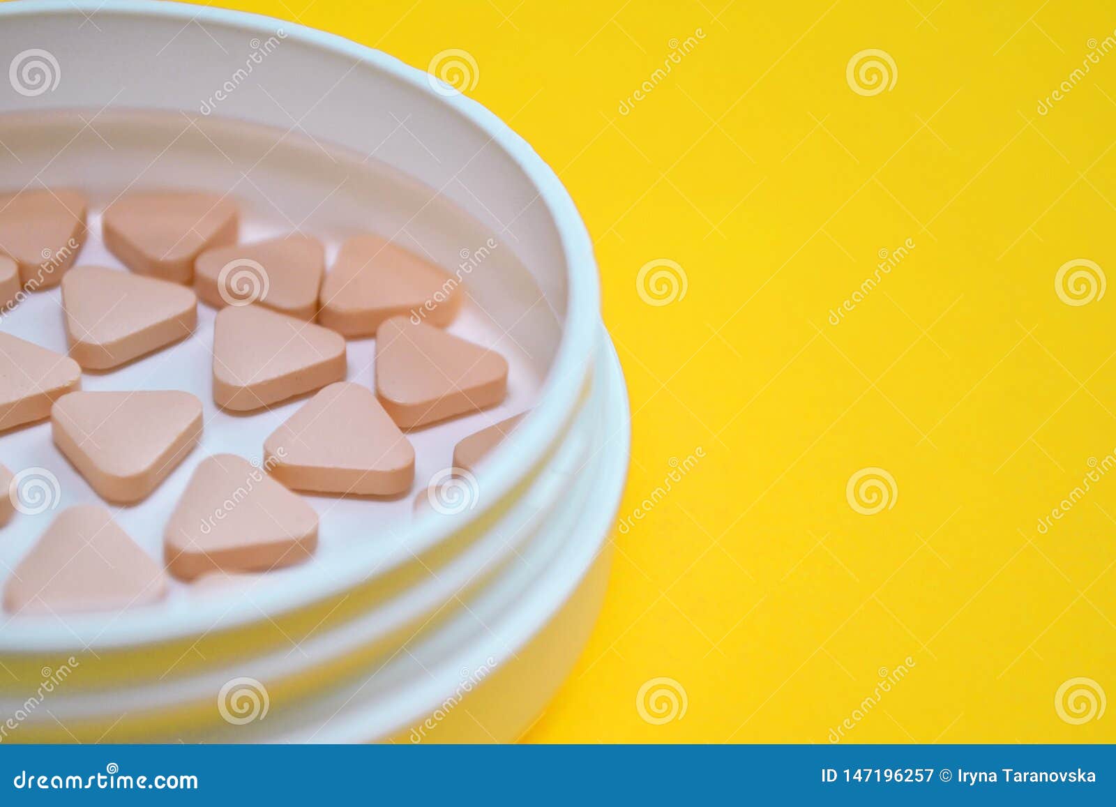 Pink Triangular Unusual Pills in a White Round Box on a Yellow ...