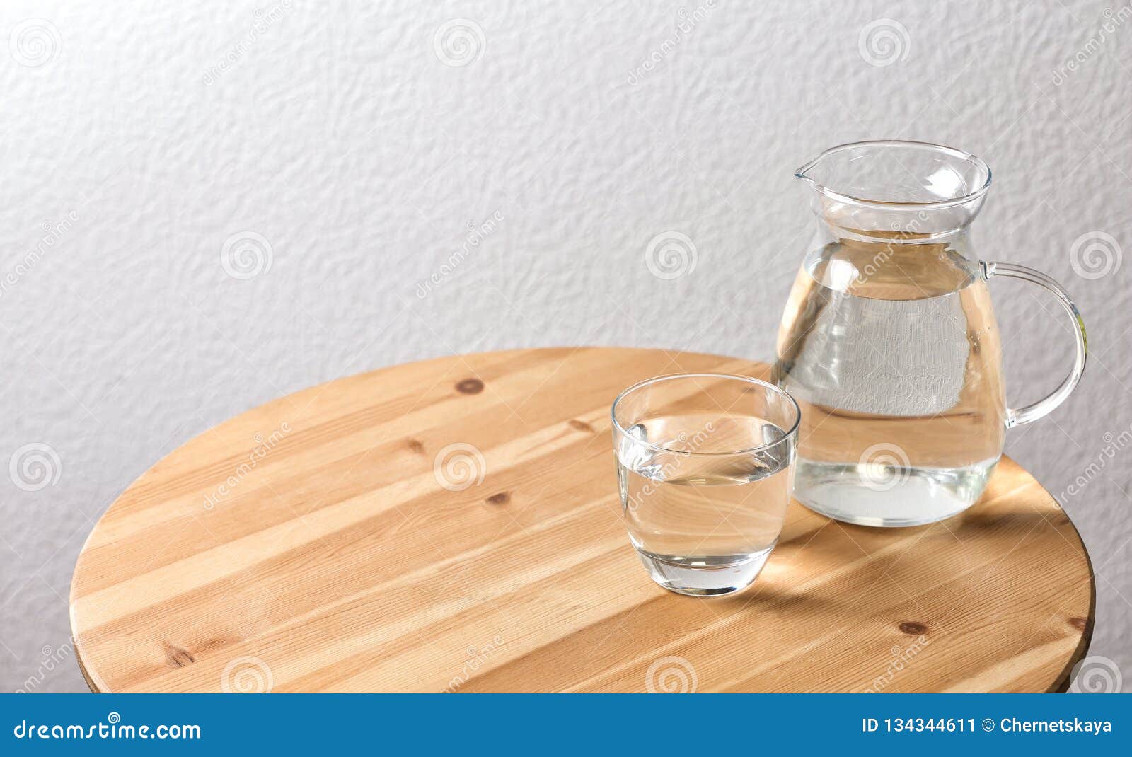 Pitcher and Glass with Water on Table Near White Wall Stock Image ...