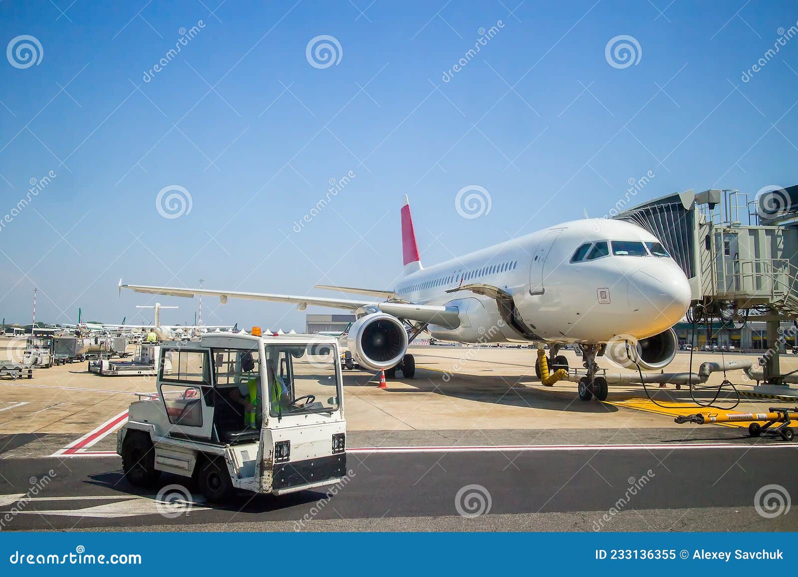 Plane at the Airport during Loading Passengers. Near the Tractor ...