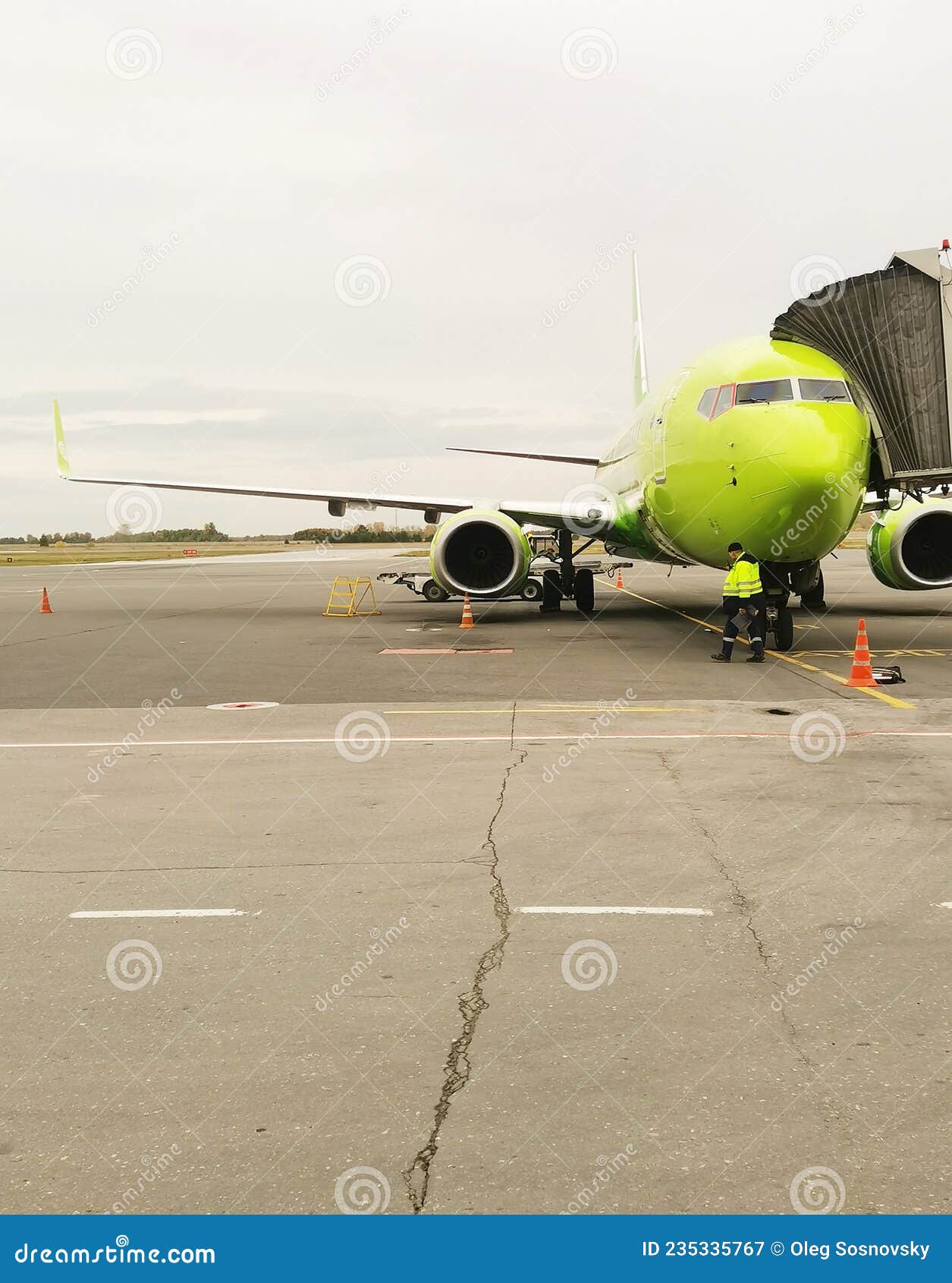 A Green Passenger Plane Stands at the Airport with a Passenger Gangway ...