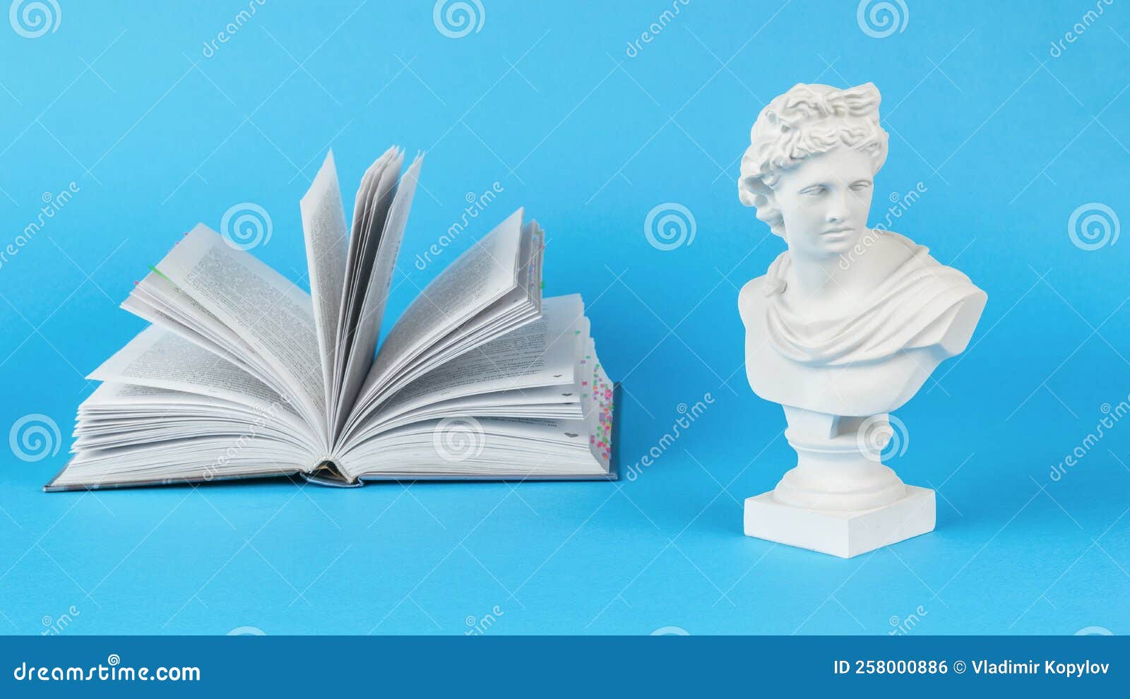 A Plaster Statuette and a Large Open Book on a Blue Background. Minimal ...