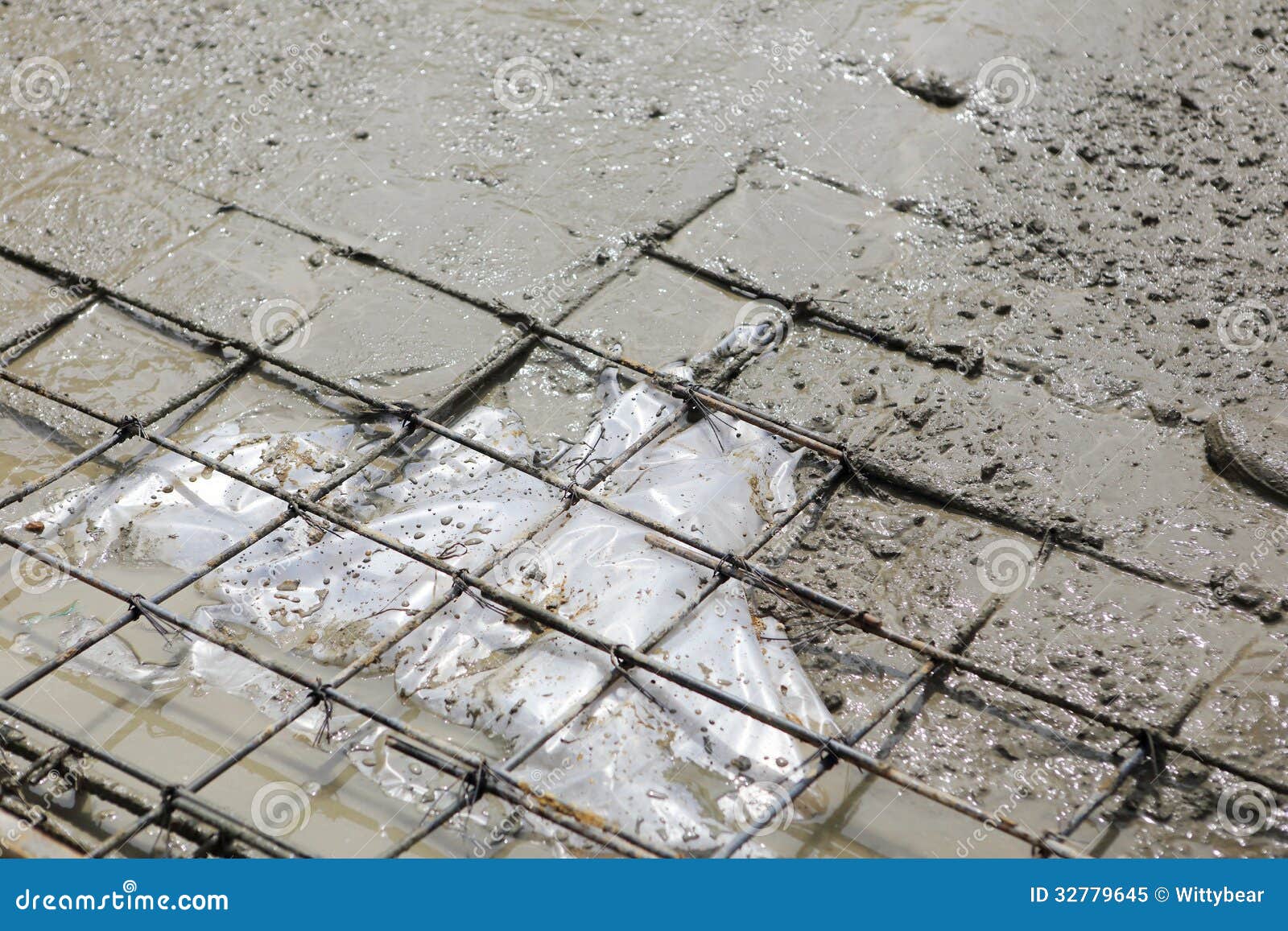 A Concrete Worker Levels The Wet Mud While Straddling The Forms ...