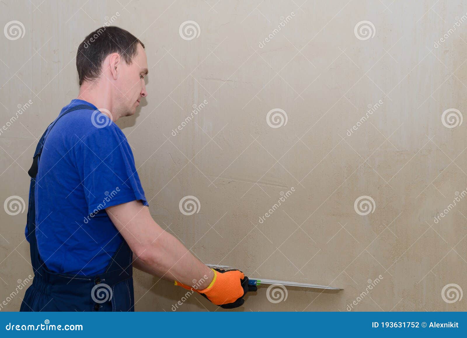 A Plasterer in Overalls Puts White Putty on Wall Stock Photo - Image of ...