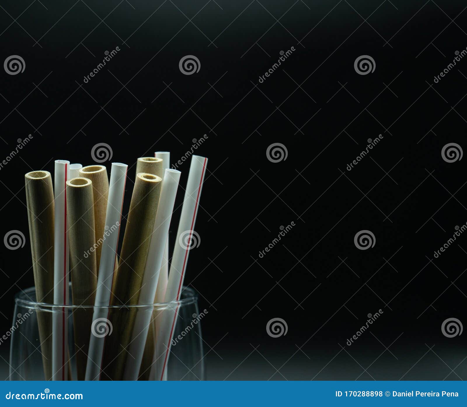 Plastic and Bamboo Straws Inside a Glass on a Black Background. Copy ...