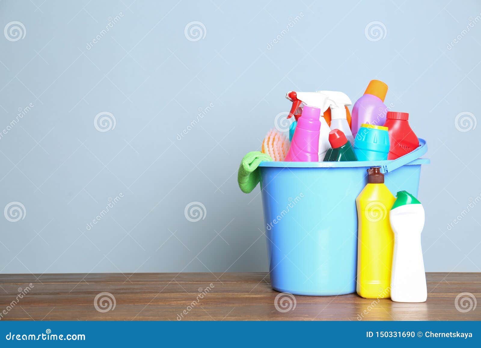 Plastic Bucket with Different Cleaning Products on Table Against Color ...