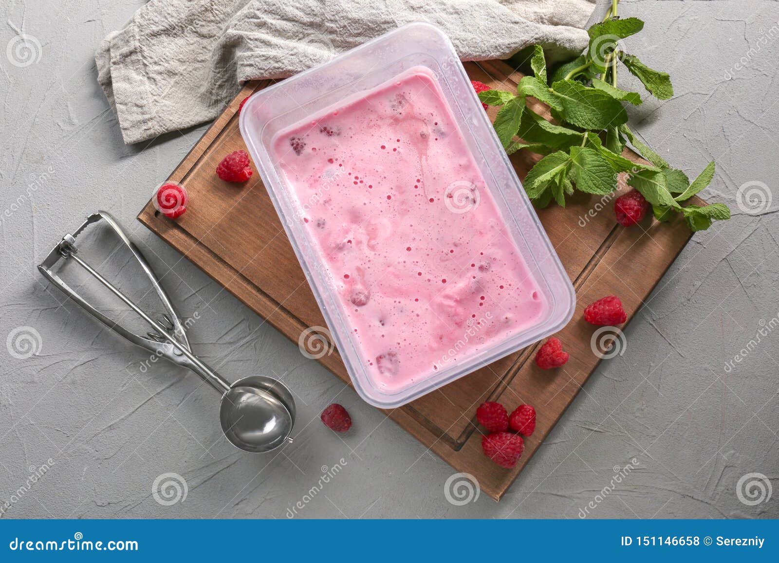 Plastic Container with Delicious Raspberry Ice-cream on Wooden Board ...